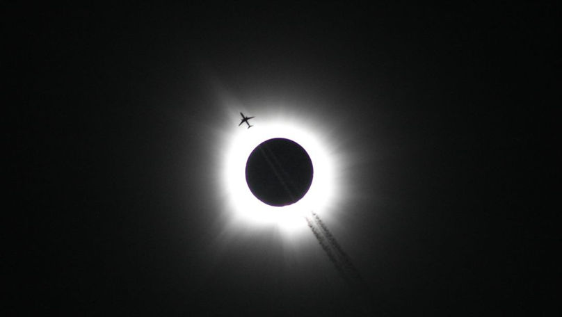 O imagine care a surprins un avion, Luna și Soarele în timpul eclipsei